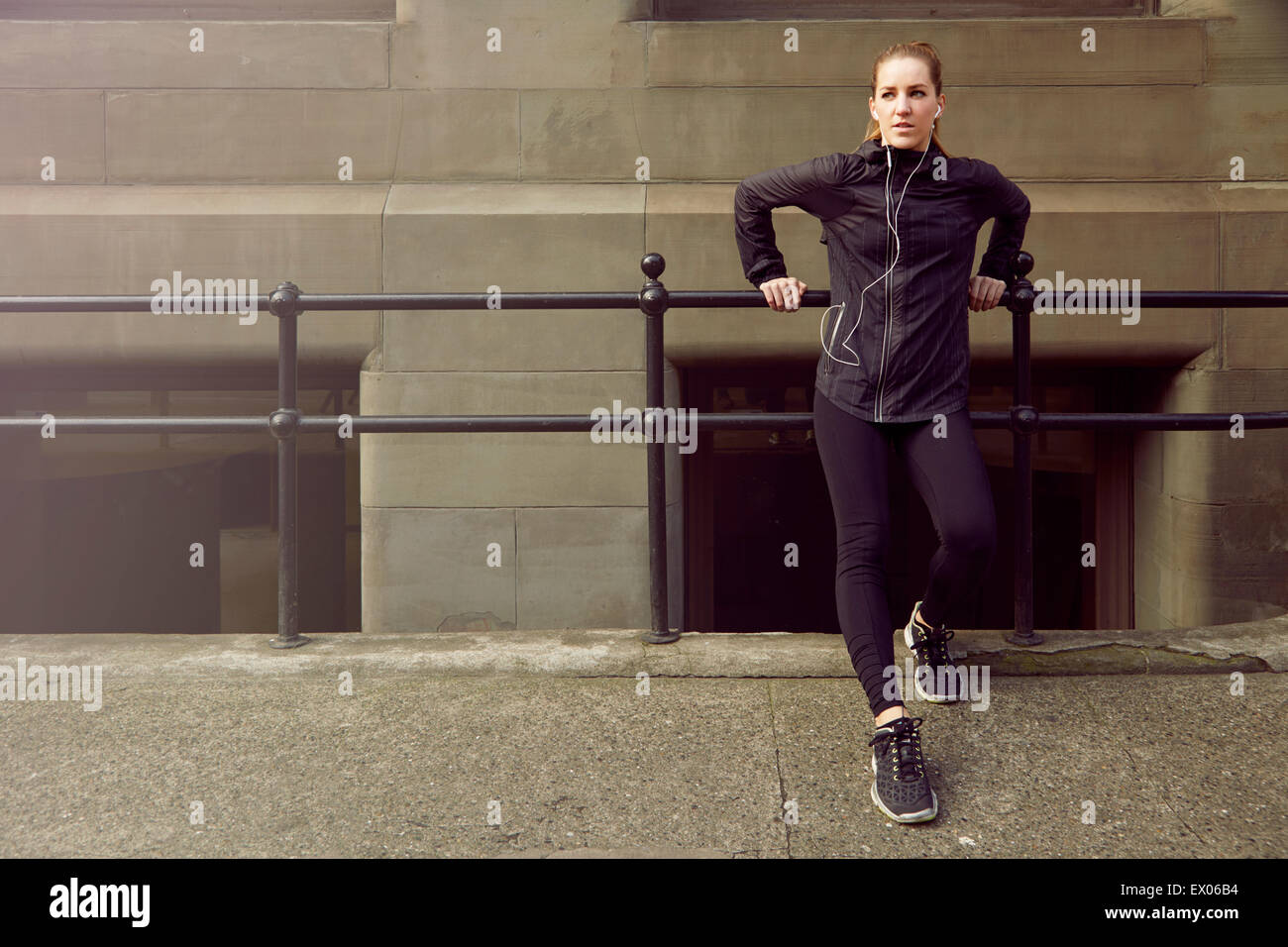 Young female runner taking a break on sidewalk Stock Photo - Alamy