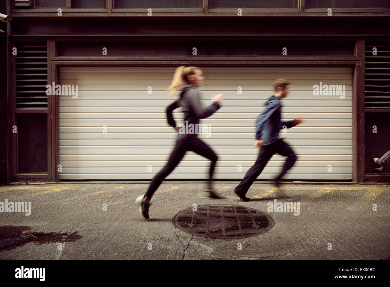 Young man and woman running along city sidewalk Stock Photo - Alamy