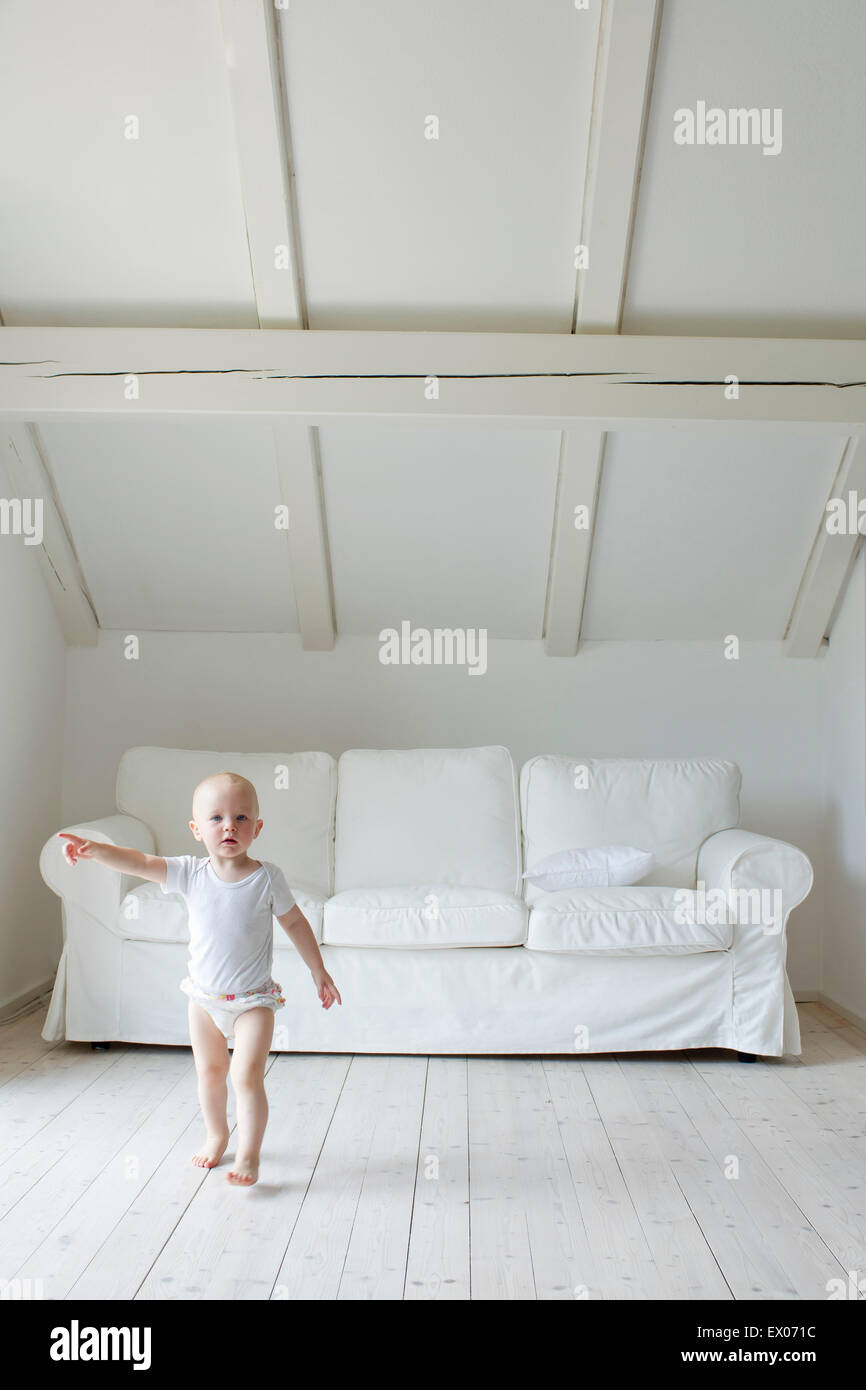 Portrait of baby girl toddling and pointing in living room Stock Photo ...