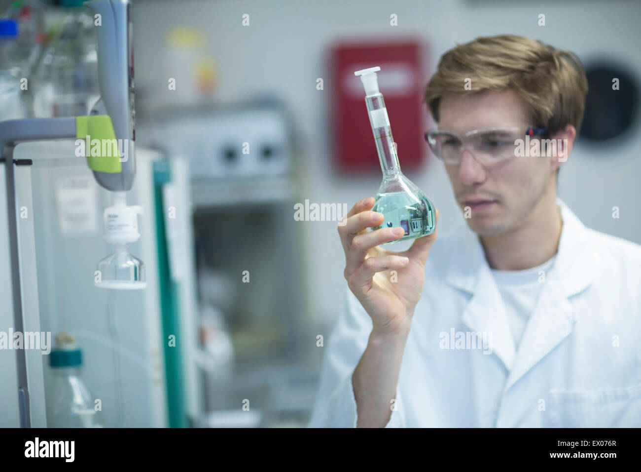 Male scientist looking at flask in lab Stock Photo - Alamy