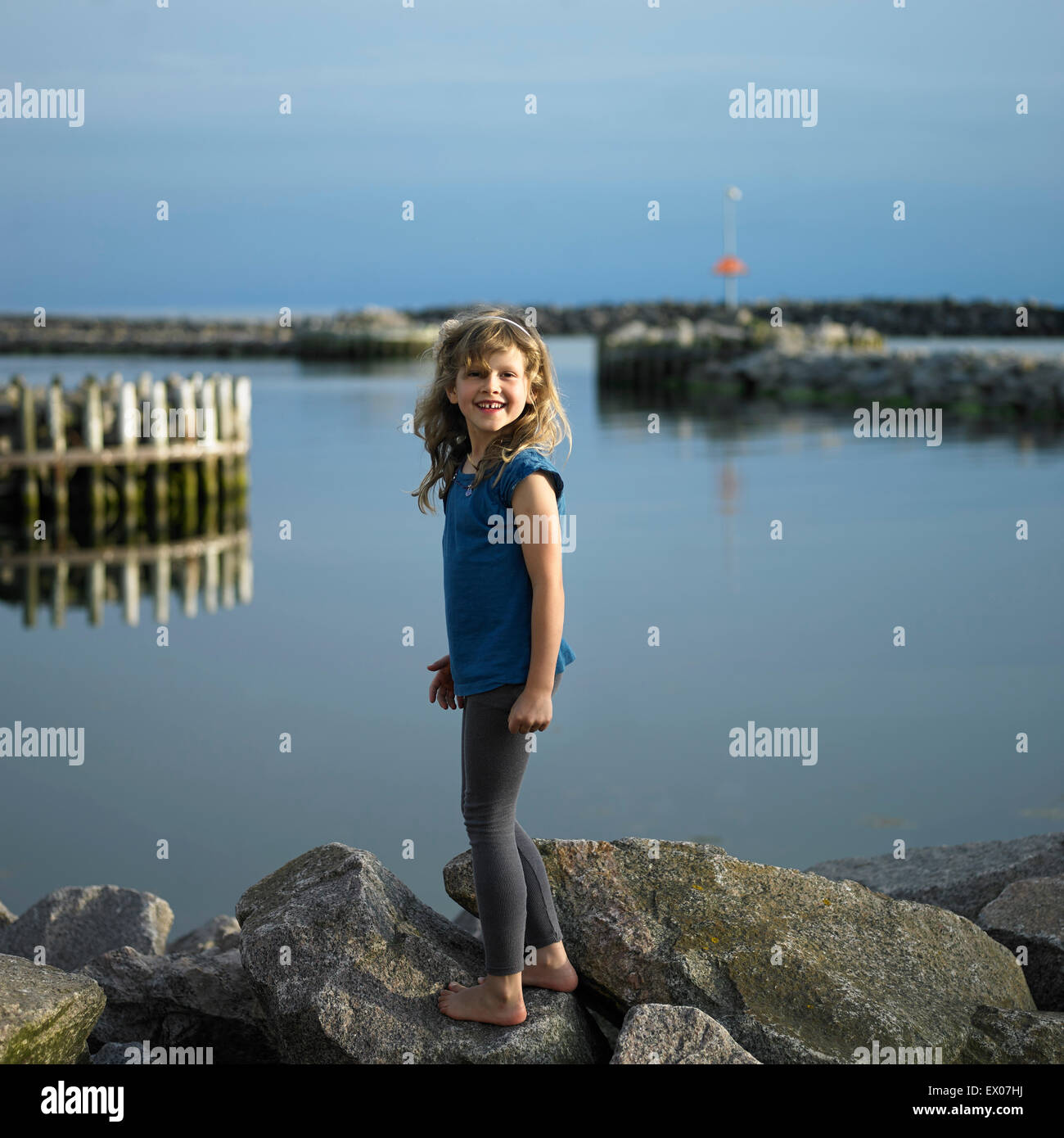 Girl standing on rock by lake Stock Photo - Alamy