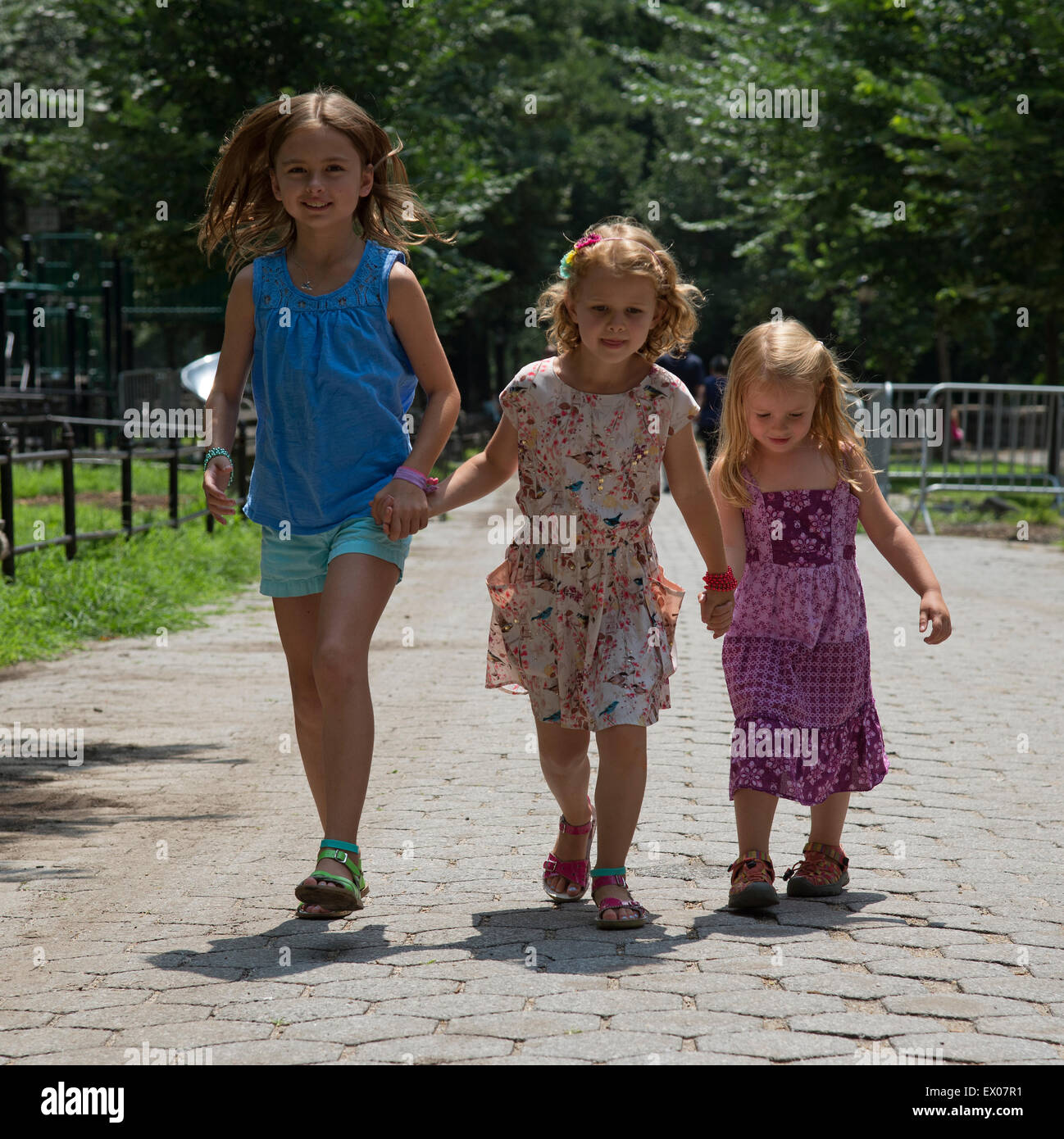 Girls having fun in a park running skipping along a footpath. New York ...