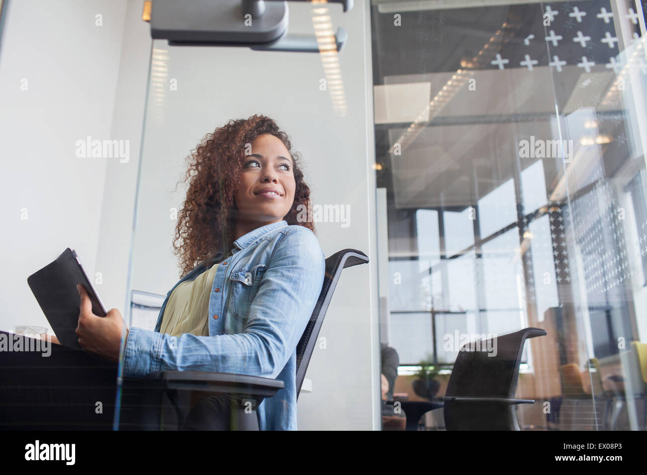 Portrait of young woman looking over her shoulder from office desk ...