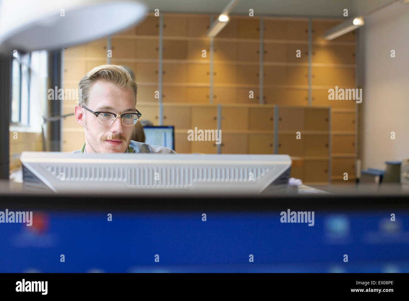 Young man using computer at office desk Stock Photo - Alamy