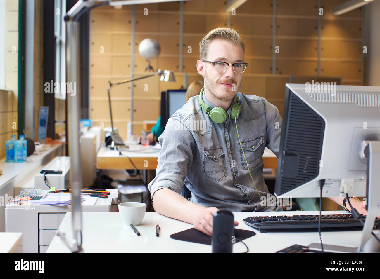 Portrait of young man using computer at office desk Stock Photo - Alamy