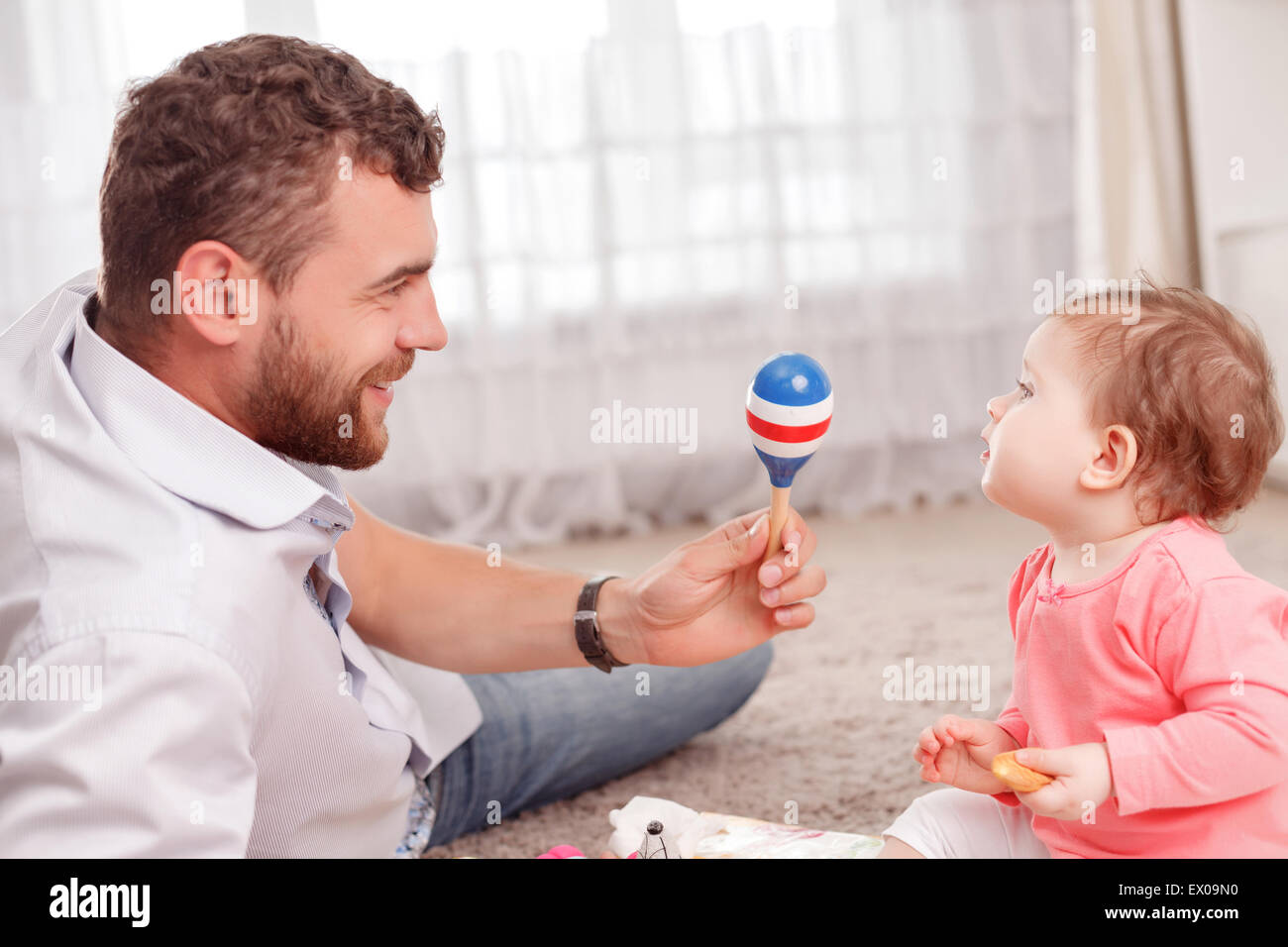 Nice young father holding rattle Stock Photo - Alamy