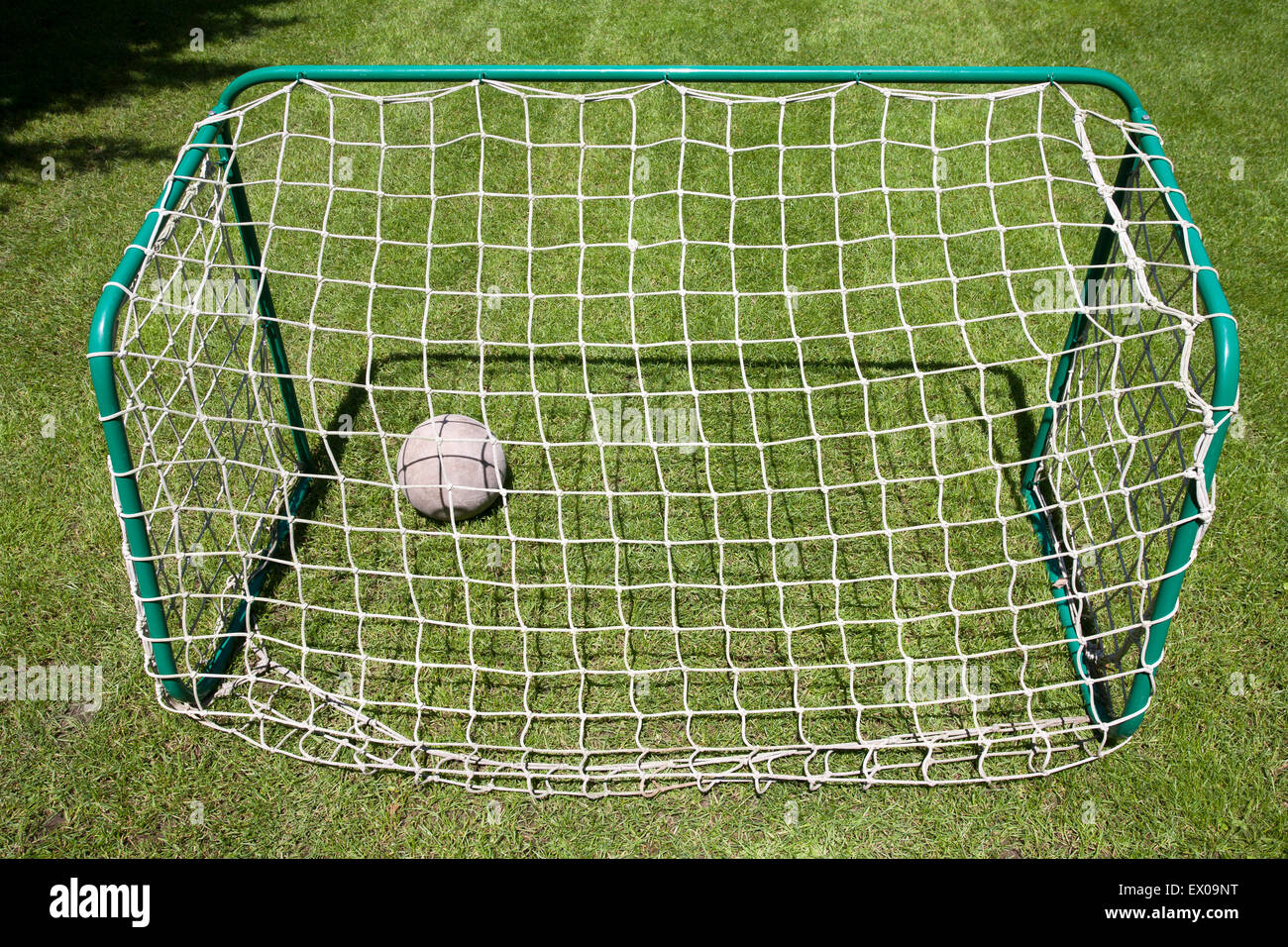 Small football gate with net and ball on the ply-field as a background ...