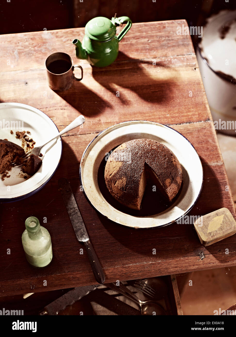 Rustic table with dish of steamed treacle pudding and teapot Stock ...