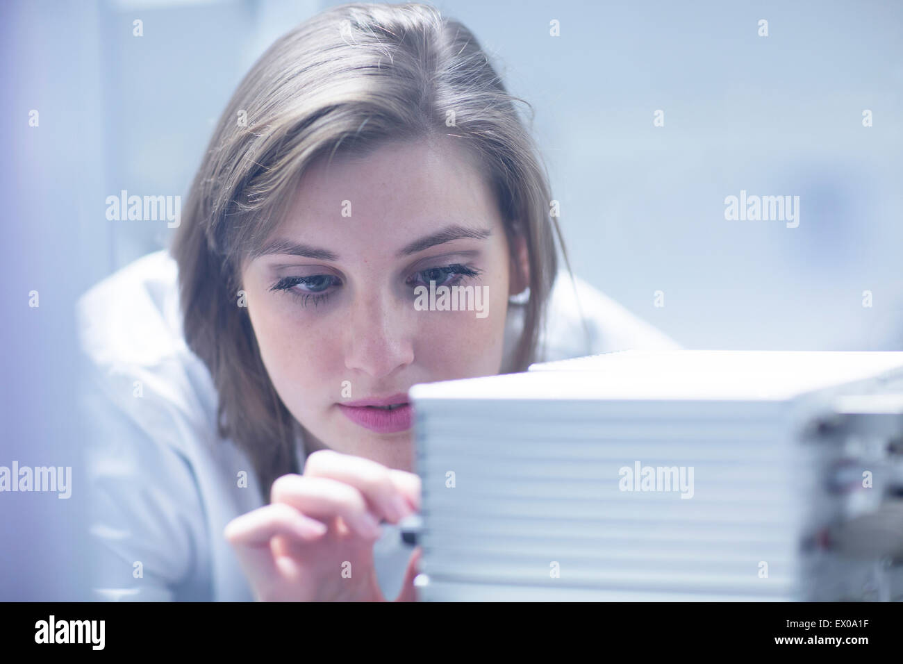 Young female scientist in lab using control panel on scanning electron ...