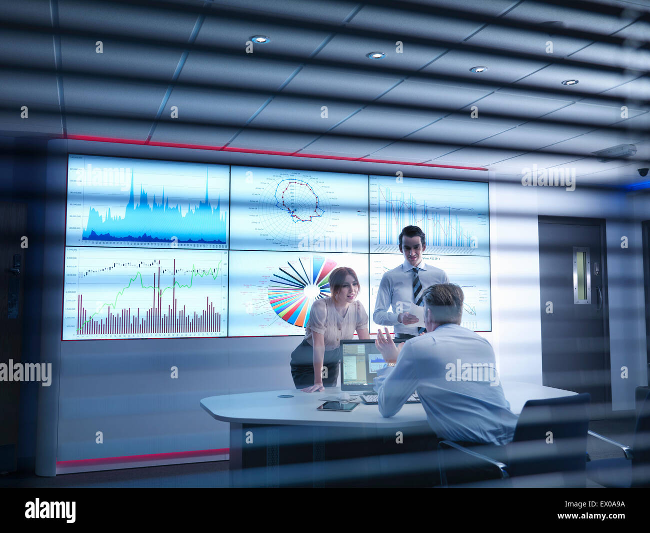 Business colleagues discussing graphs on screen in meeting room Stock ...