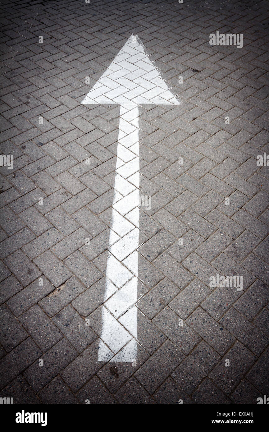 White directional arrow sign on a road Stock Photo - Alamy
