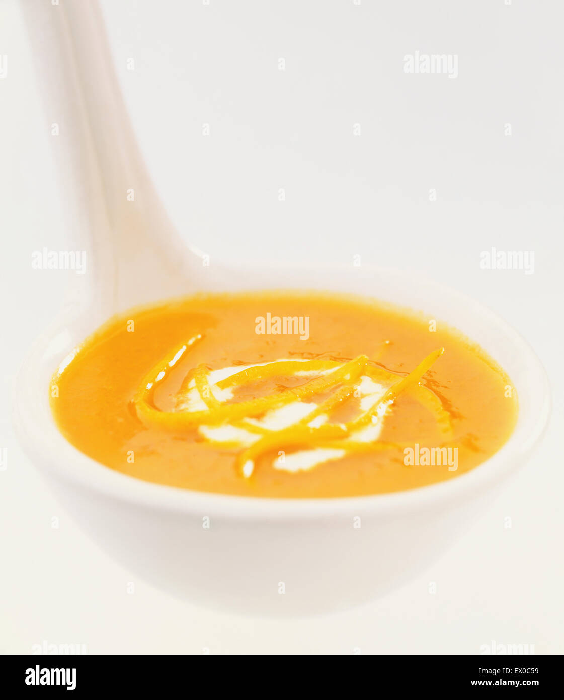 White ceramic ladle filled with mashed, orange coloured soup, garnished ...