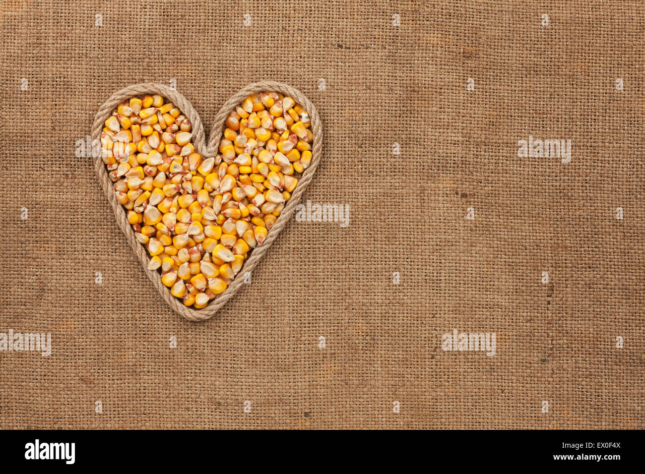 Heart made from rope with corn grains lying on sackcloth, with space ...
