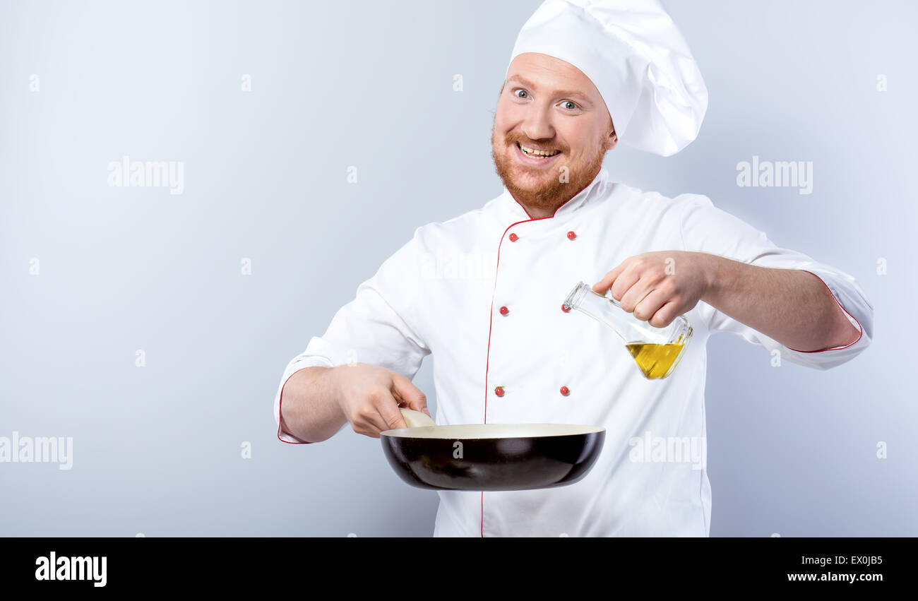 Head-cook holding pan and pouring olive oil in it Stock Photo - Alamy