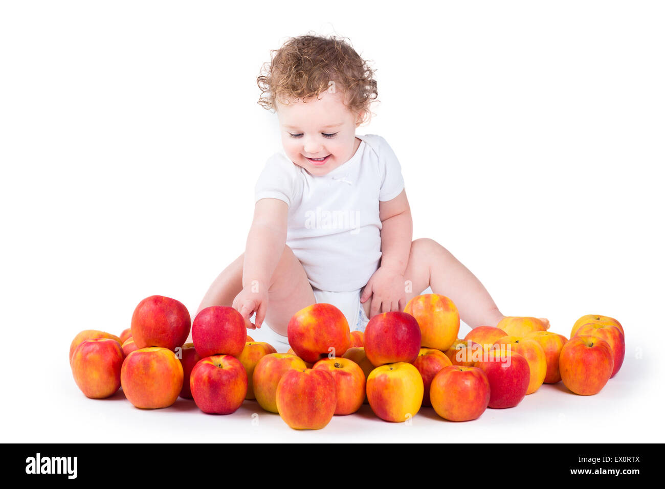Happy laughing baby girl playing with red and yellow apples on white ...