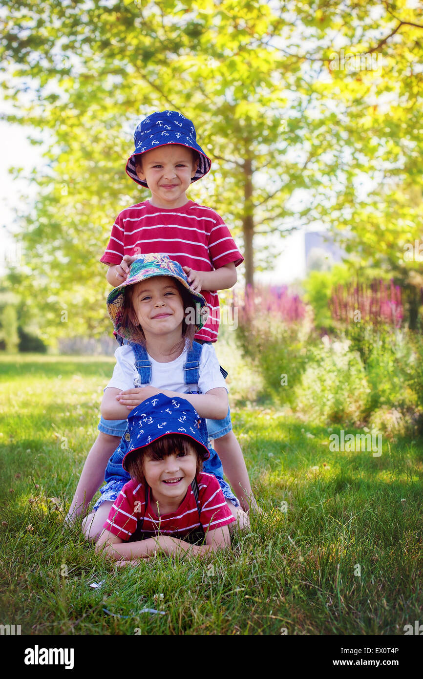 Three kids in the park, standing one over the other, smiling and having ...