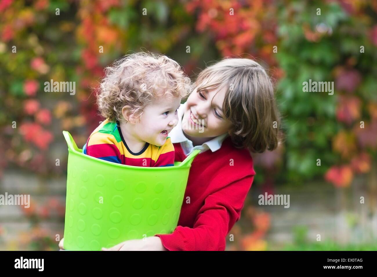 Happy laughing brother and baby sister playing together in the garden ...