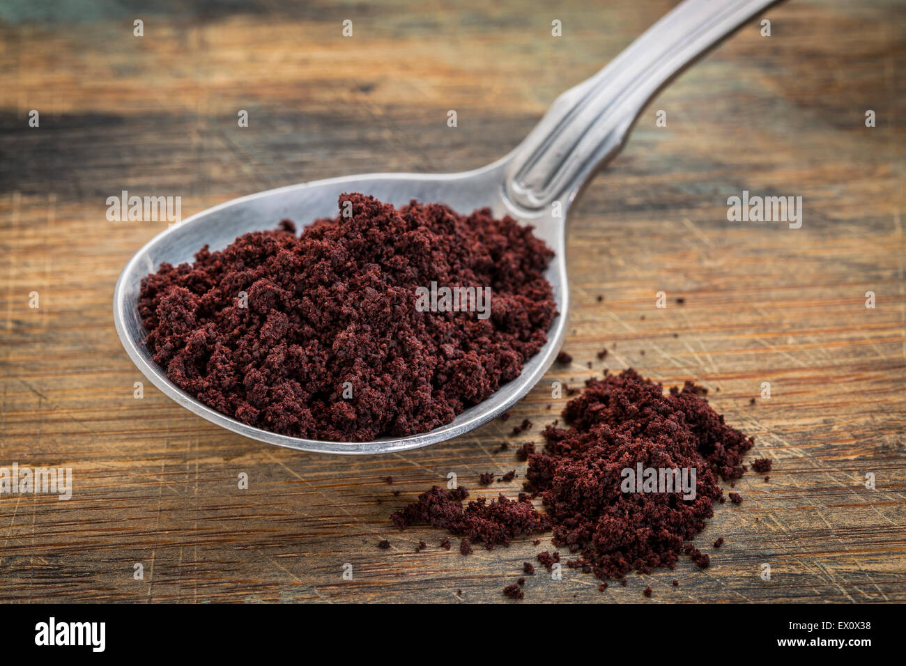 acai berry powder on tablespoon against rustic wooden cutting board ...