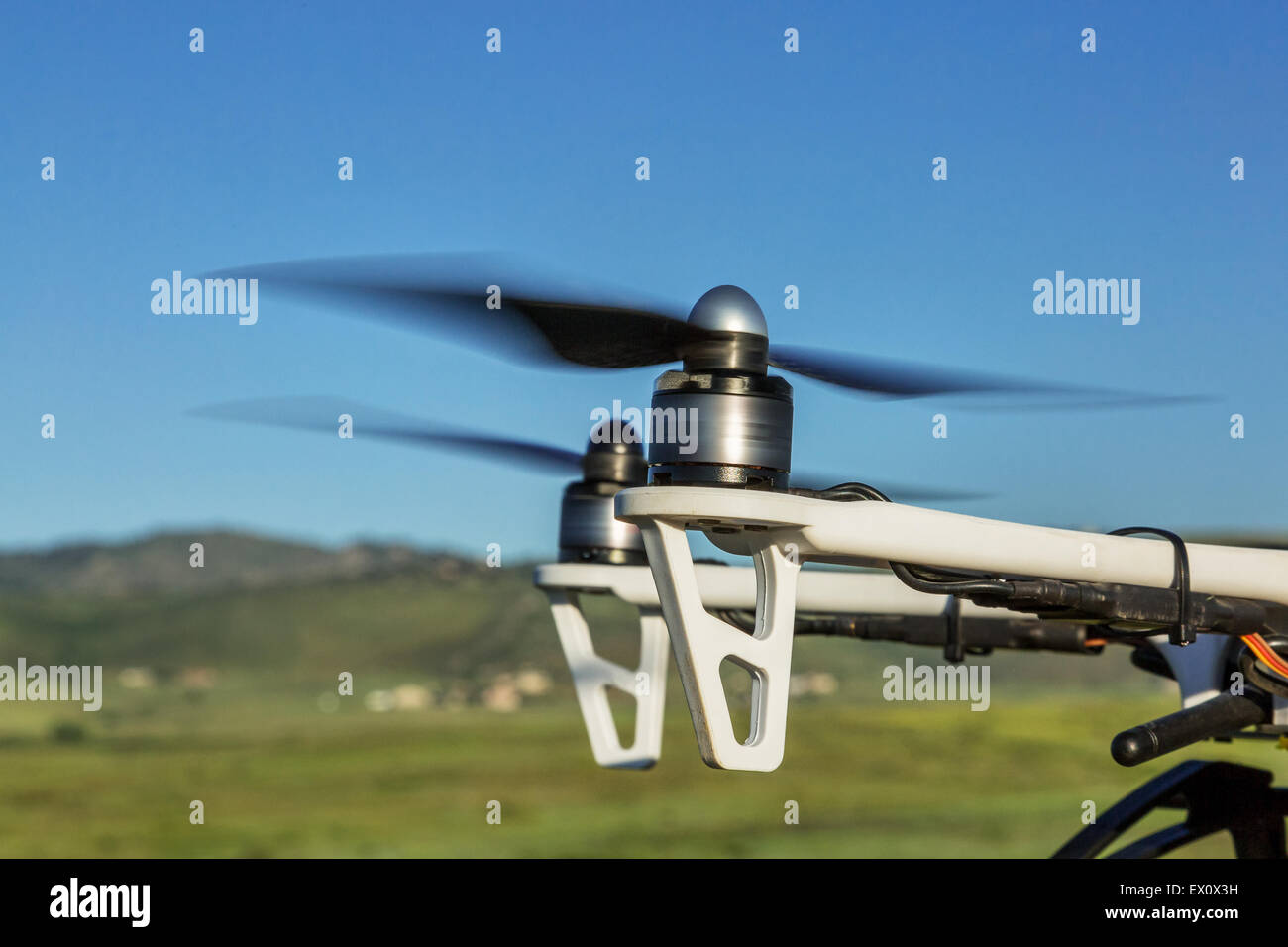 blurred spinning propellers of a hexacopter drone flying over foothills ...
