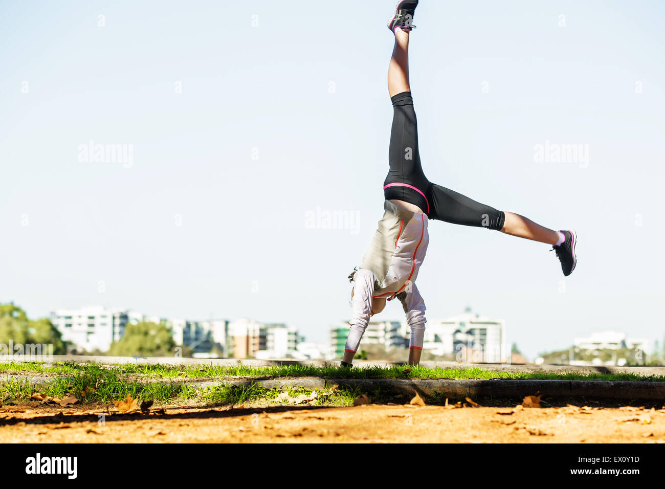 Young fit woman doing simple acrobatics exercise routine in autumn park ...