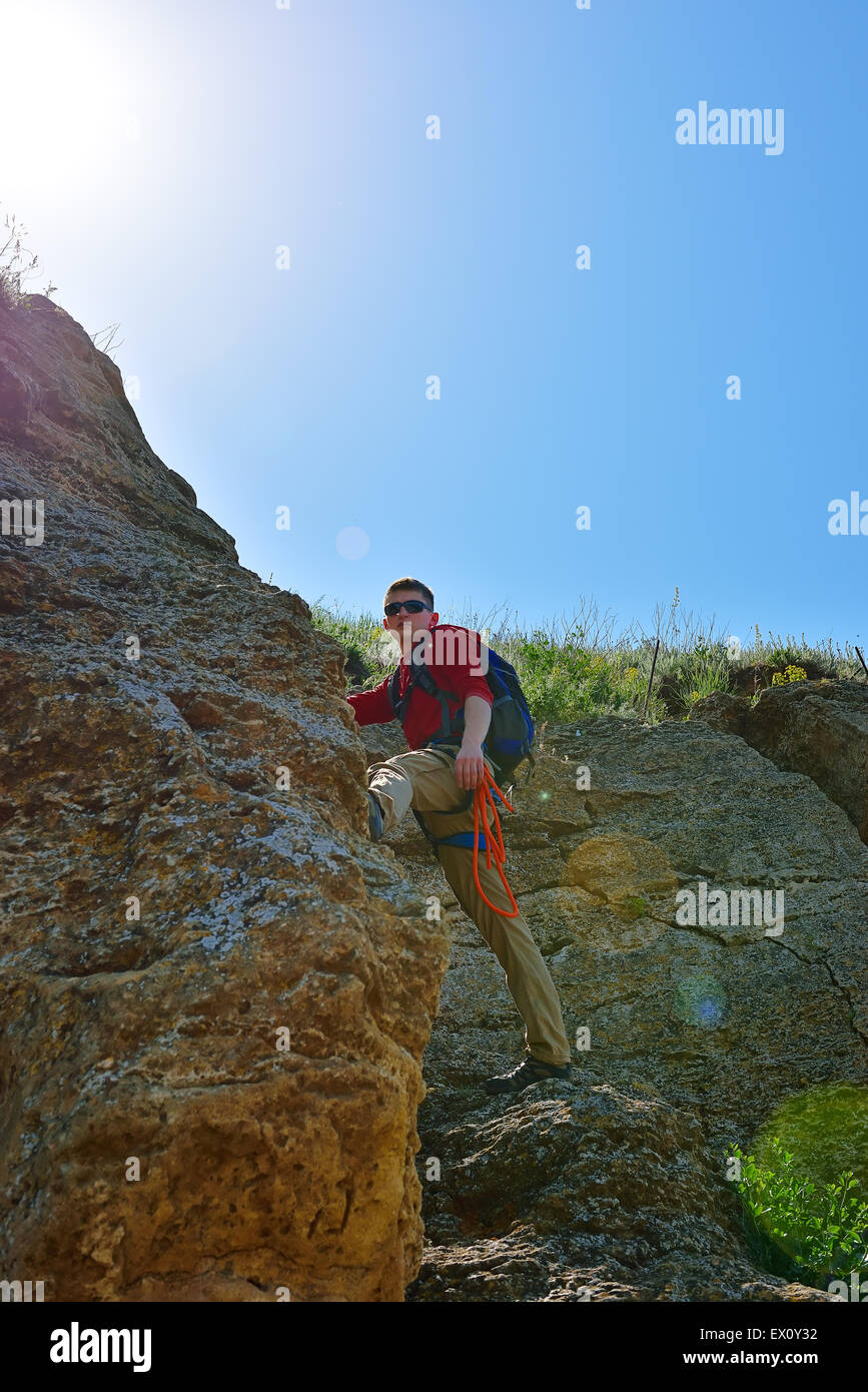 young climber with backpack climbing up a cliff Stock Photo - Alamy