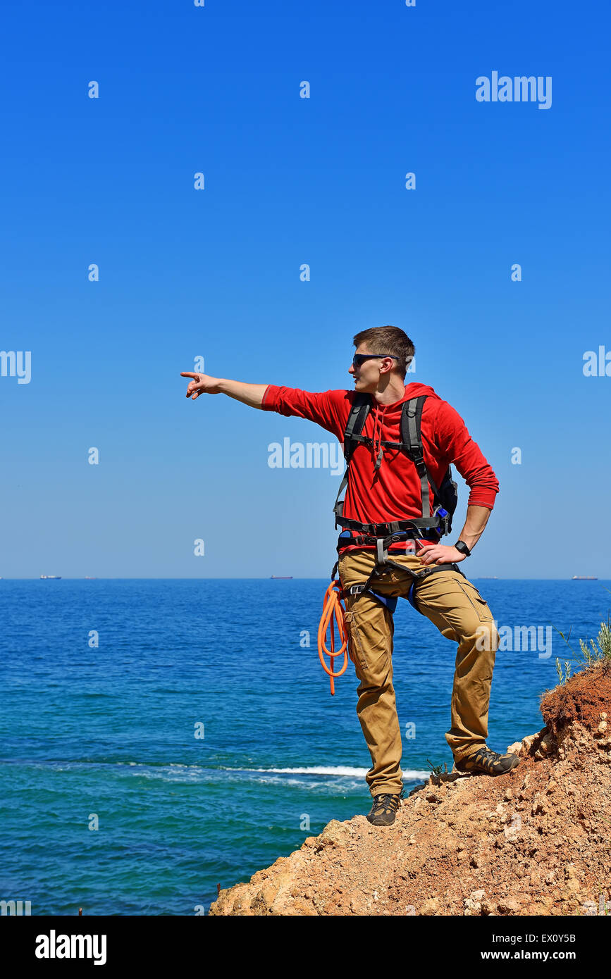 climber man with backpack on top of mountain pointing to ocean Stock ...