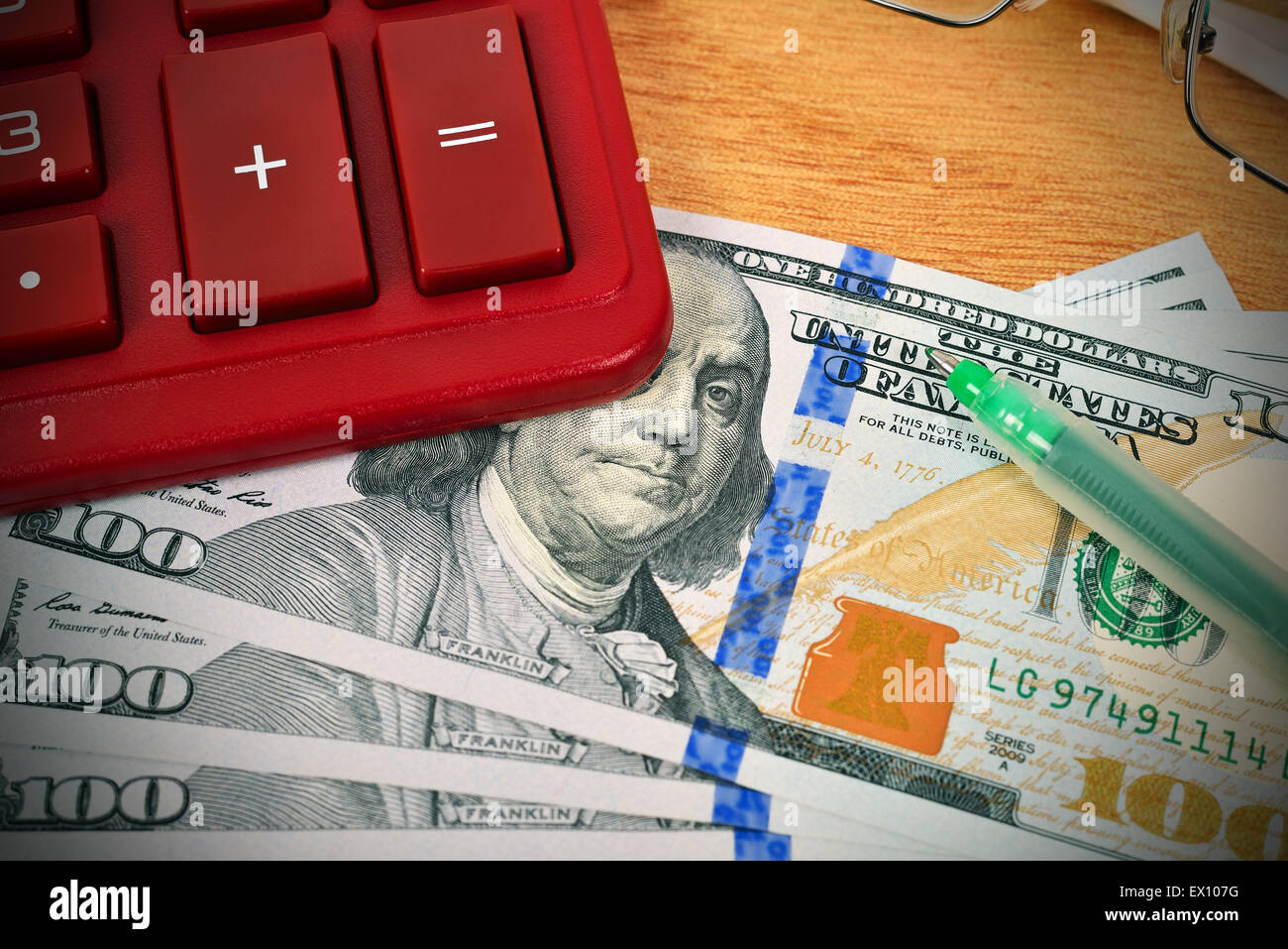Stack of dollar bills with a calculator and pen Stock Photo - Alamy