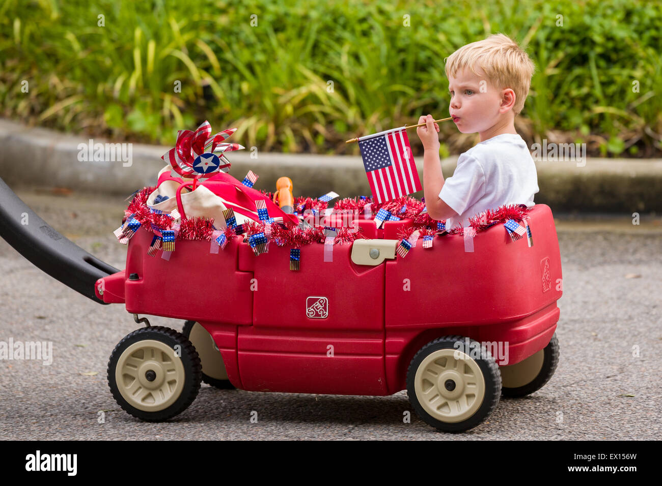 A child rides along in a wagon decorated in patriotic colors wearing ...