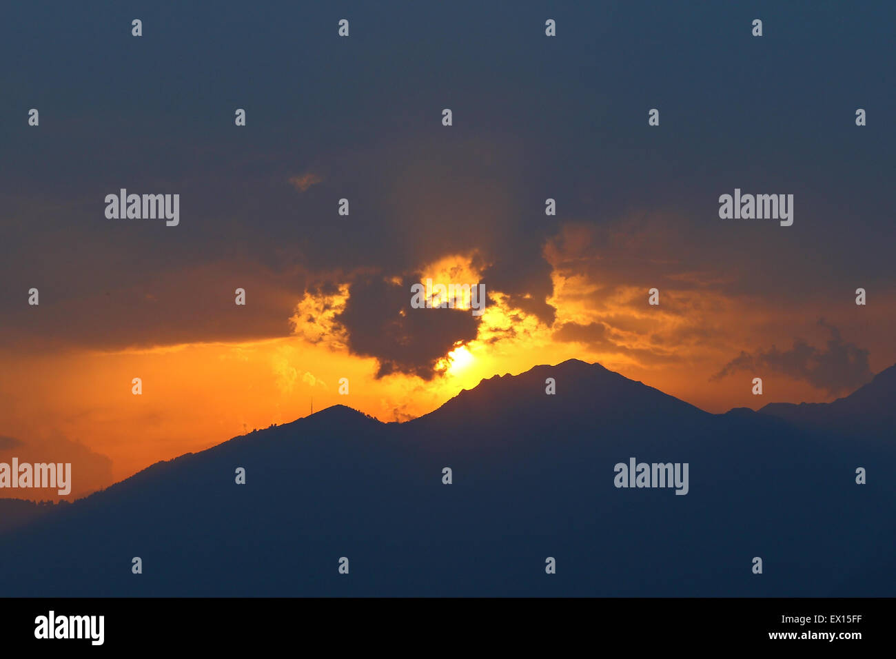 Sun peeking through dissipating storm clouds at sunset over the Alps ...