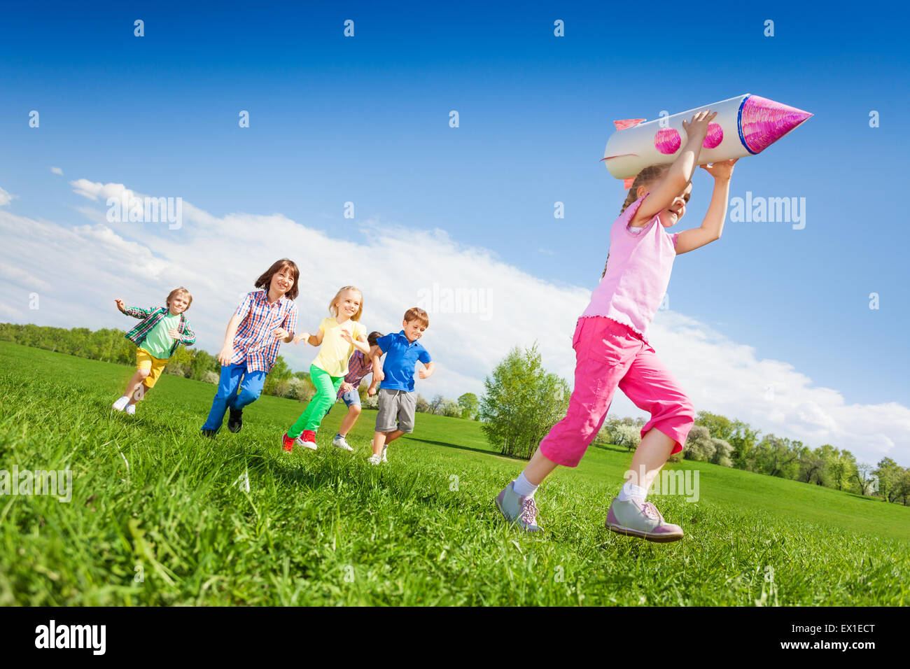 Small girl holding rocket carton toy and kids run Stock Photo - Alamy