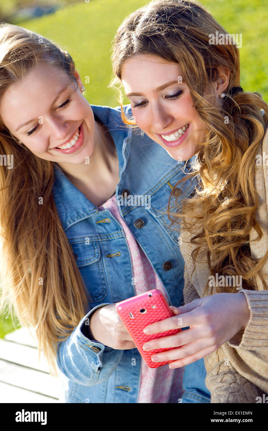 Two friends having fun with smartphones in the street Stock Photo - Alamy