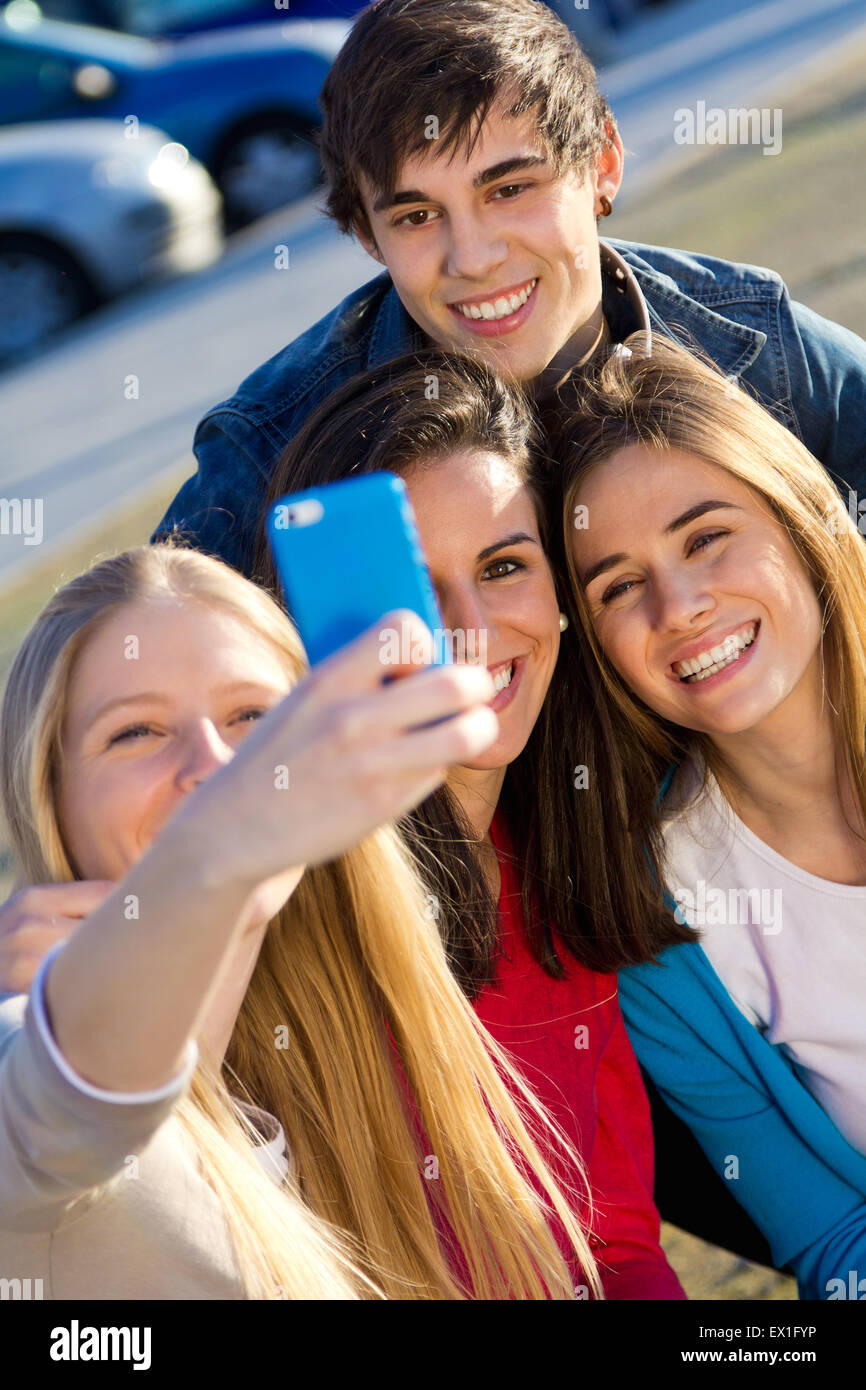 Outdoor portrait of group of friends taking photos with a smartphone in ...
