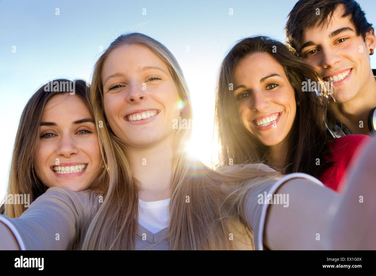Outdoor portrait of group of friends taking photos with a smartphone in ...