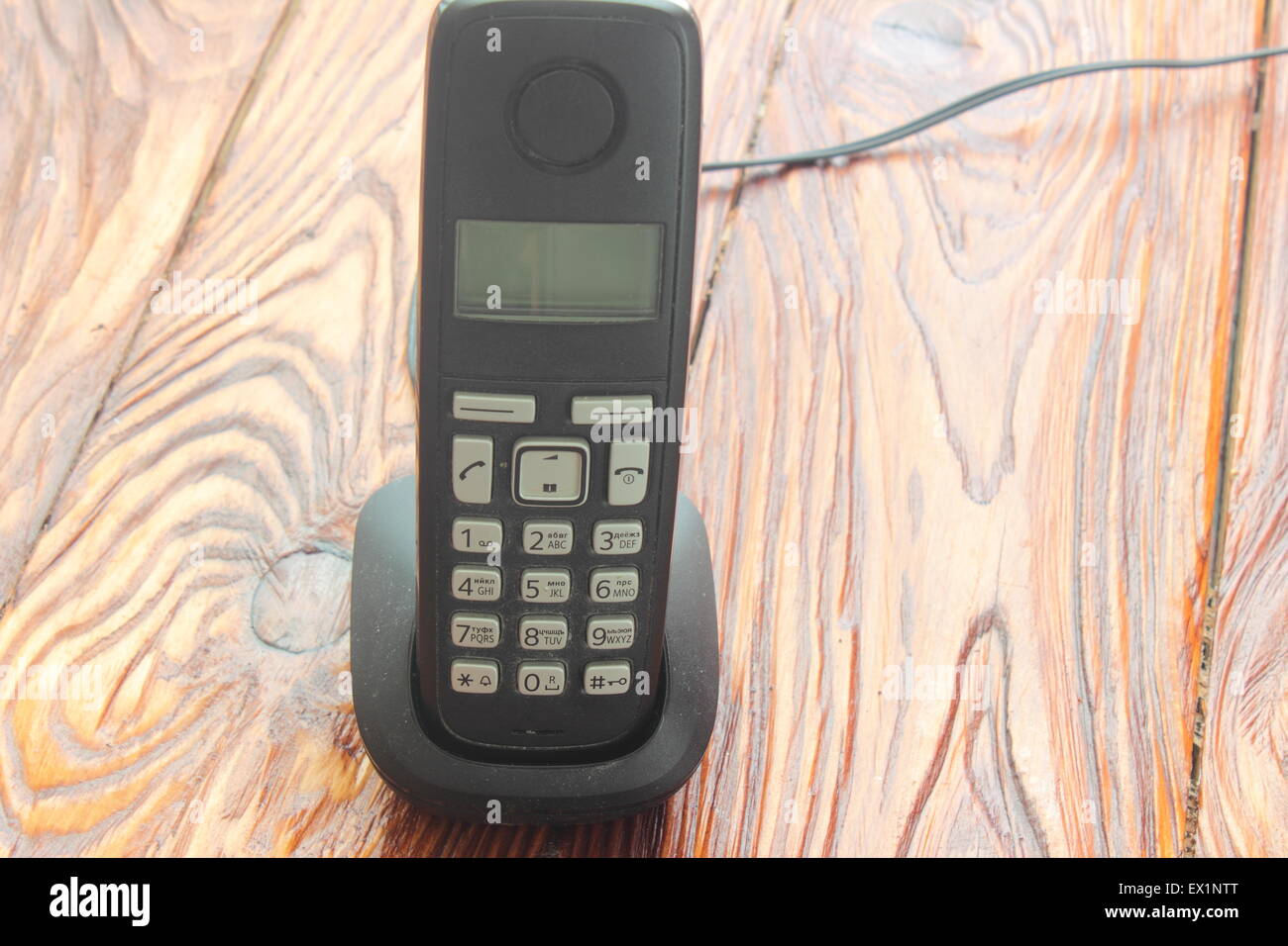on a wooden board is a cordless phone on the charging cradle Stock ...