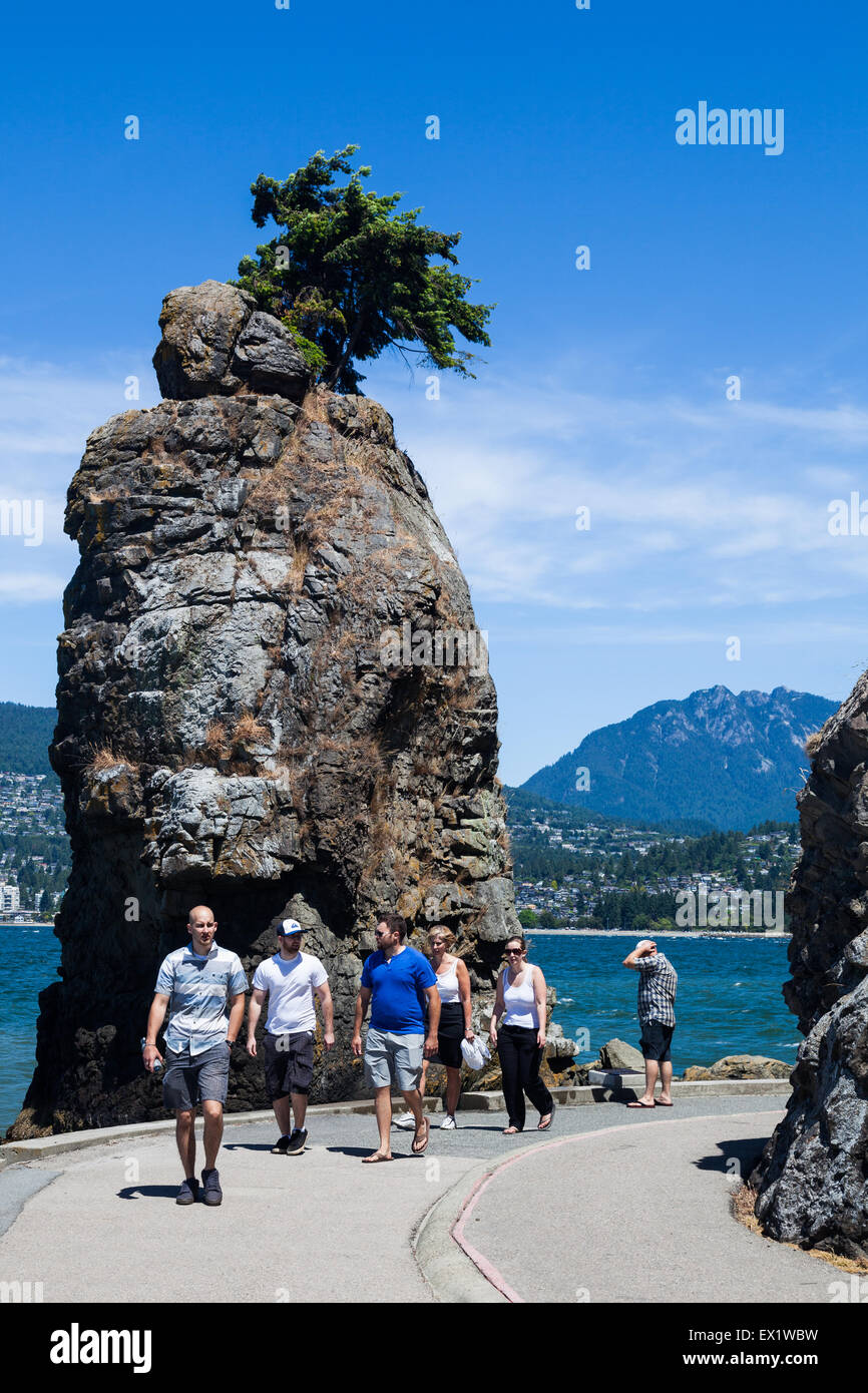 People walking past Siwash Rock as they make a circuit of Stanley Park ...