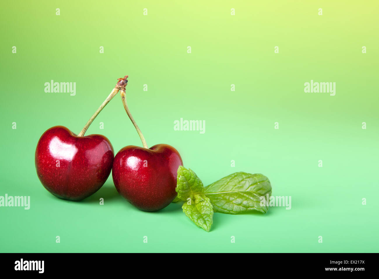 Two perfect specimen of red cherries on a green background Stock Photo ...