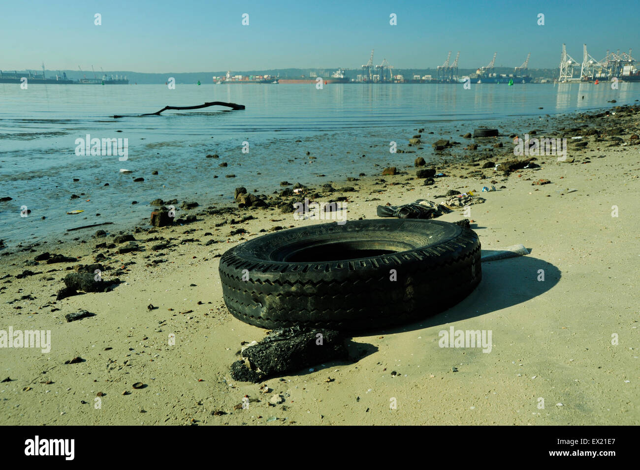 Shore pollution of black rubber vehicle tyre washed up on beach of ...