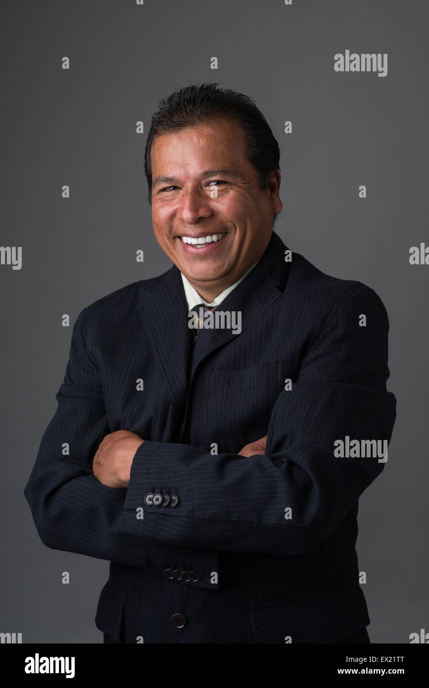 Hispanic business man smiling with arms crossed wearing a business suit posing for a portrait ...