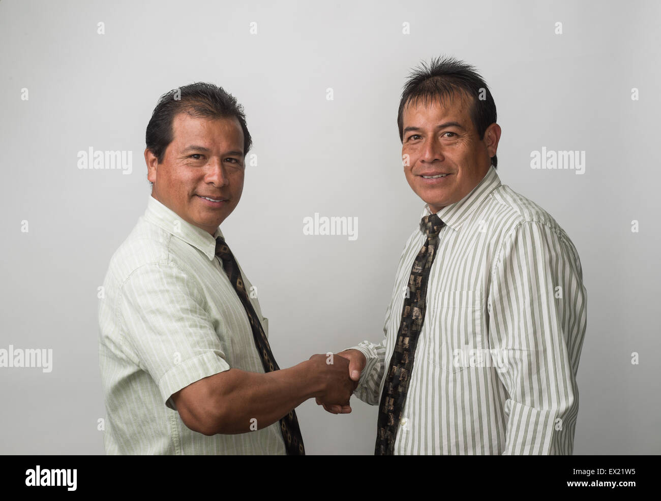 Hispanic businessmen shaking hands, negotiating and smiling Stock Photo ...