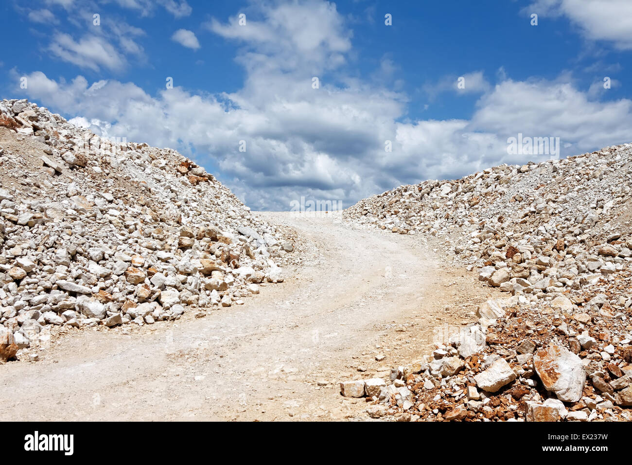 rocky road against blue sky with clouds Stock Photo - Alamy