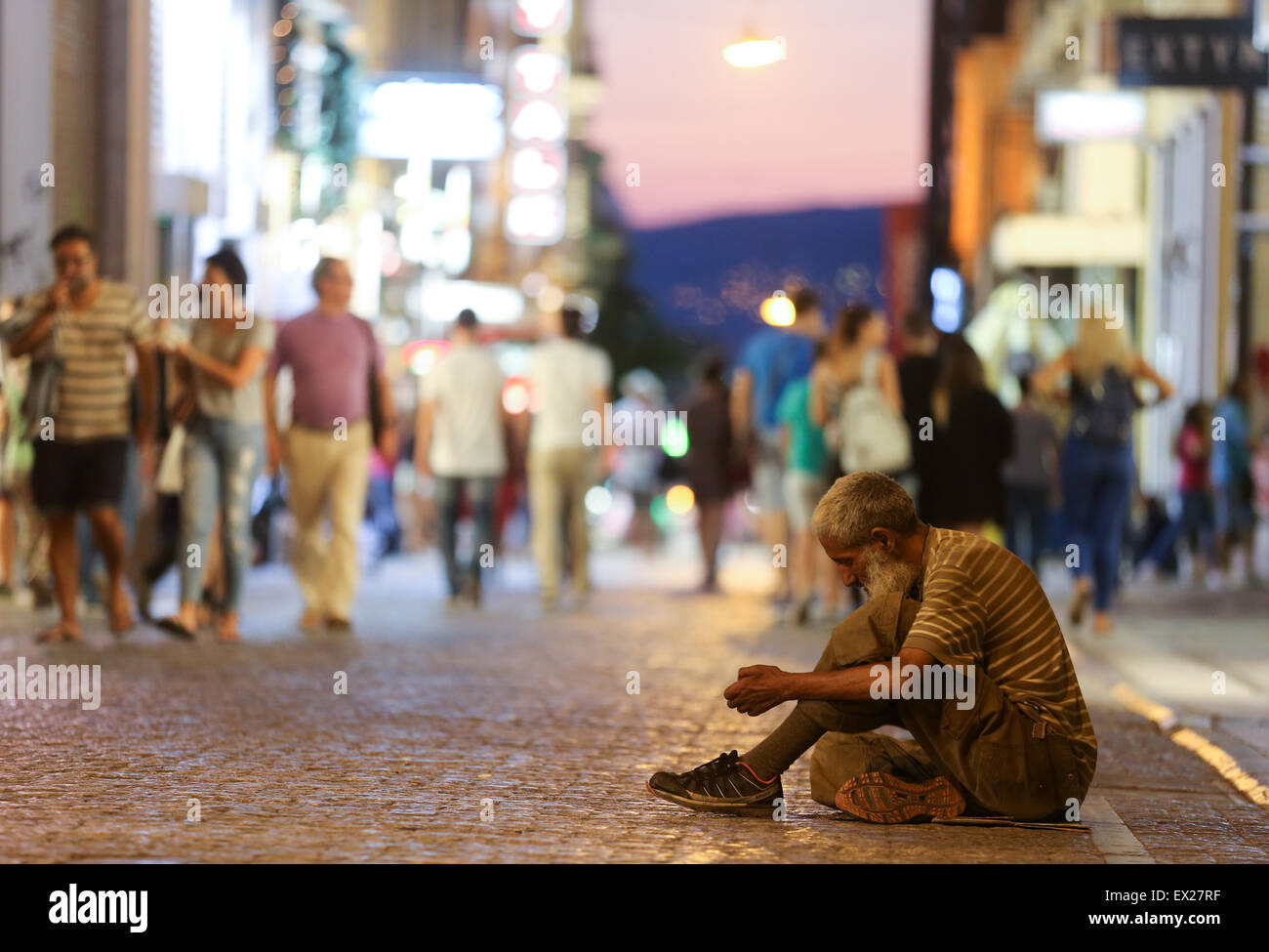 Athens, Greece. 04th July, 2015. A homeless person sits on the shopping ...