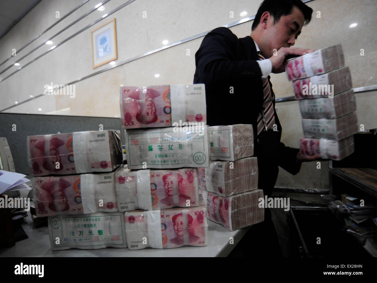 An employee packs bundles of Renminbi banknotes at a branch of Bank of ...