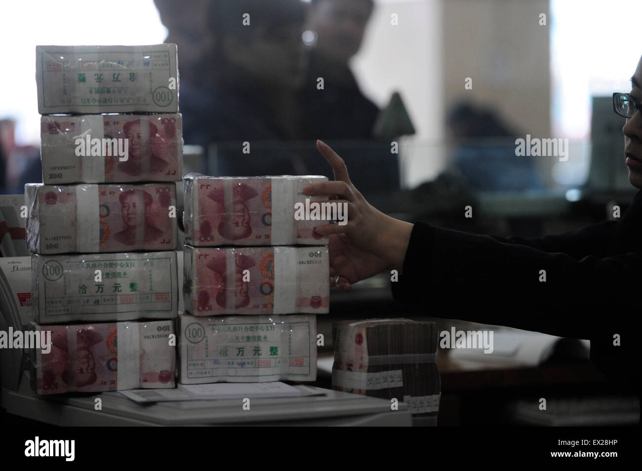 An employee packs bundles of Renminbi banknotes at a branch of Bank of ...