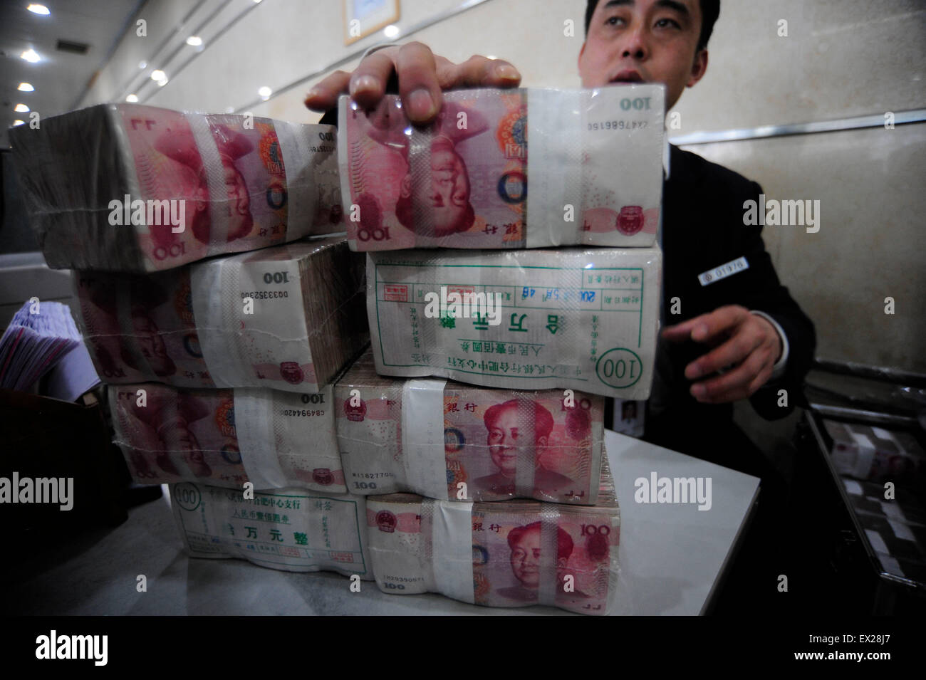 An employee packs bundles of Renminbi banknotes at a branch of Bank of ...