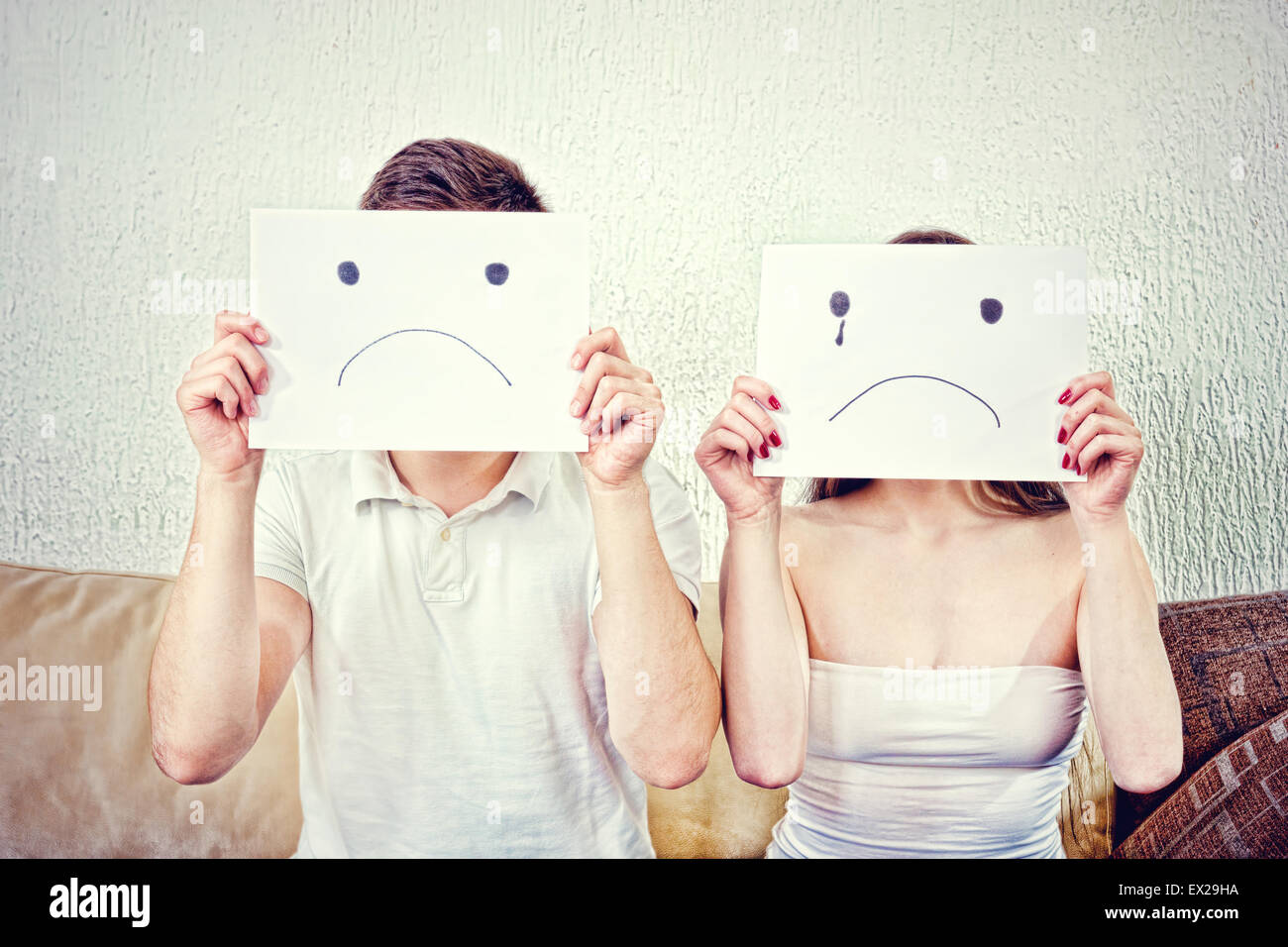 Sad young couple. Unhappy young couple in despair sitting on couch ...