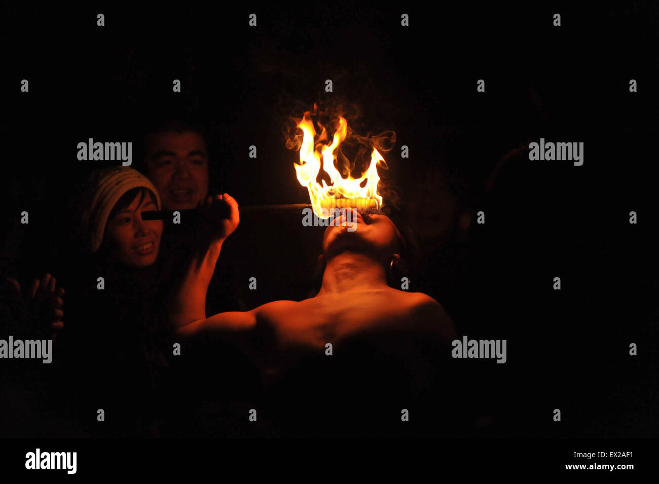 A performer places a torch into his mouth during a stunt performance ...