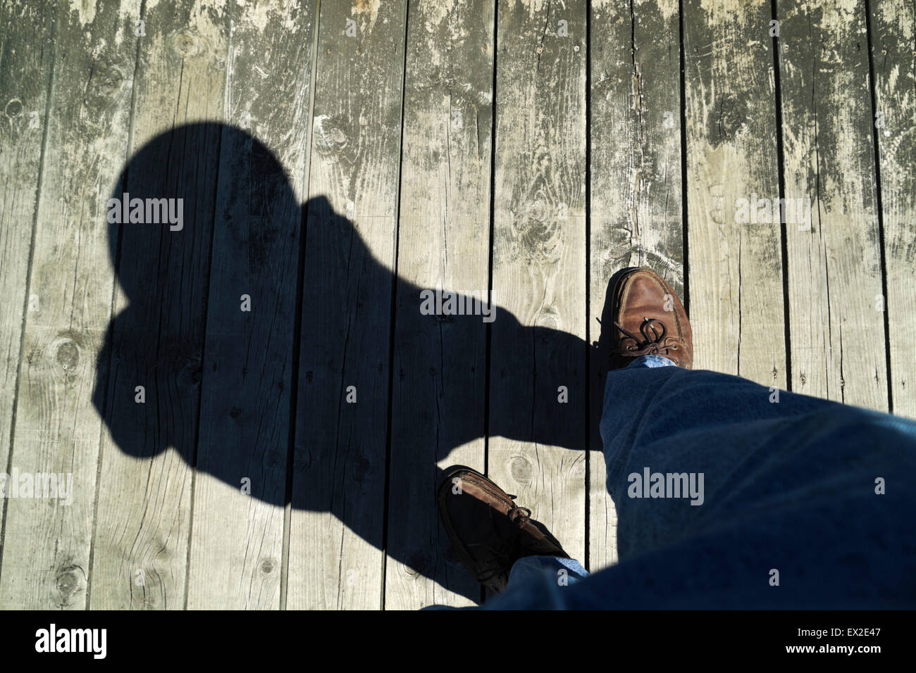 Legs and shoes of a photographer with his shadow cast on a weathered ...