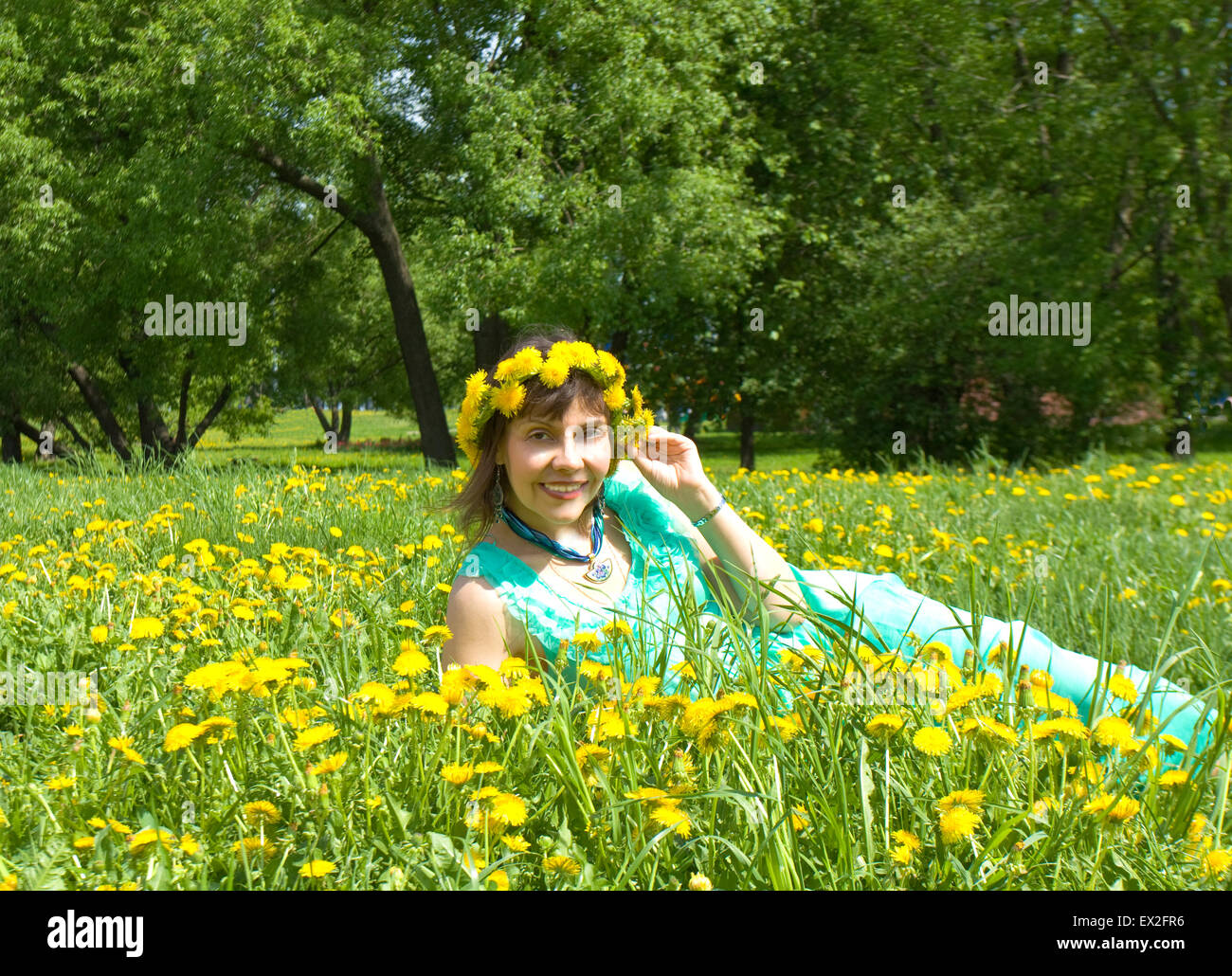 Pretty lady in wreath of yellow dandelions brunette European, laying on ...