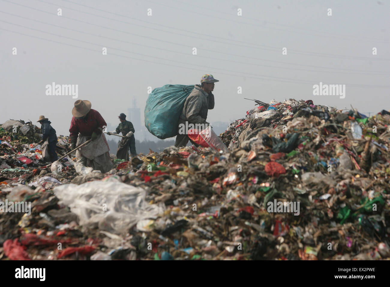 Garbage collectors search for recyclable waste at a garbage dump site ...
