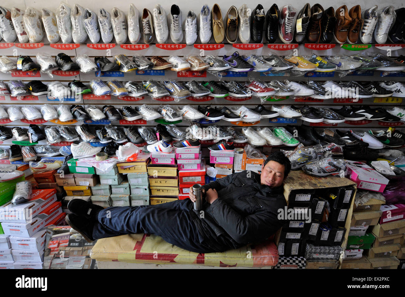 A shoe vendor naps while waits for customers at his store in Taiyuan ...